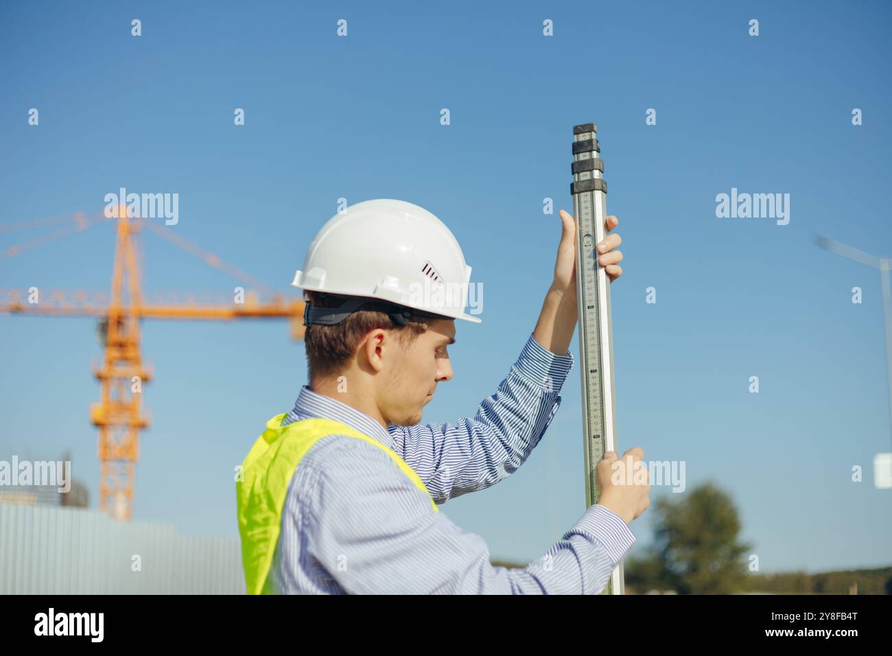 Worker is unfolding leveling rod on construction site Stock Photo - Alamy