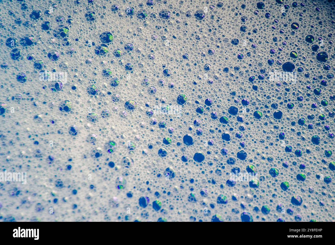 Macro view of bubbles forming on the water surface with blue background ...