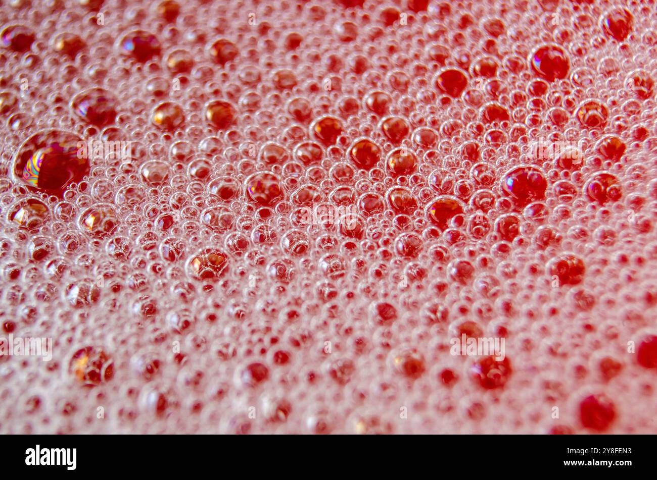 Macro shot of bubbles forming on a water surface with red background ...
