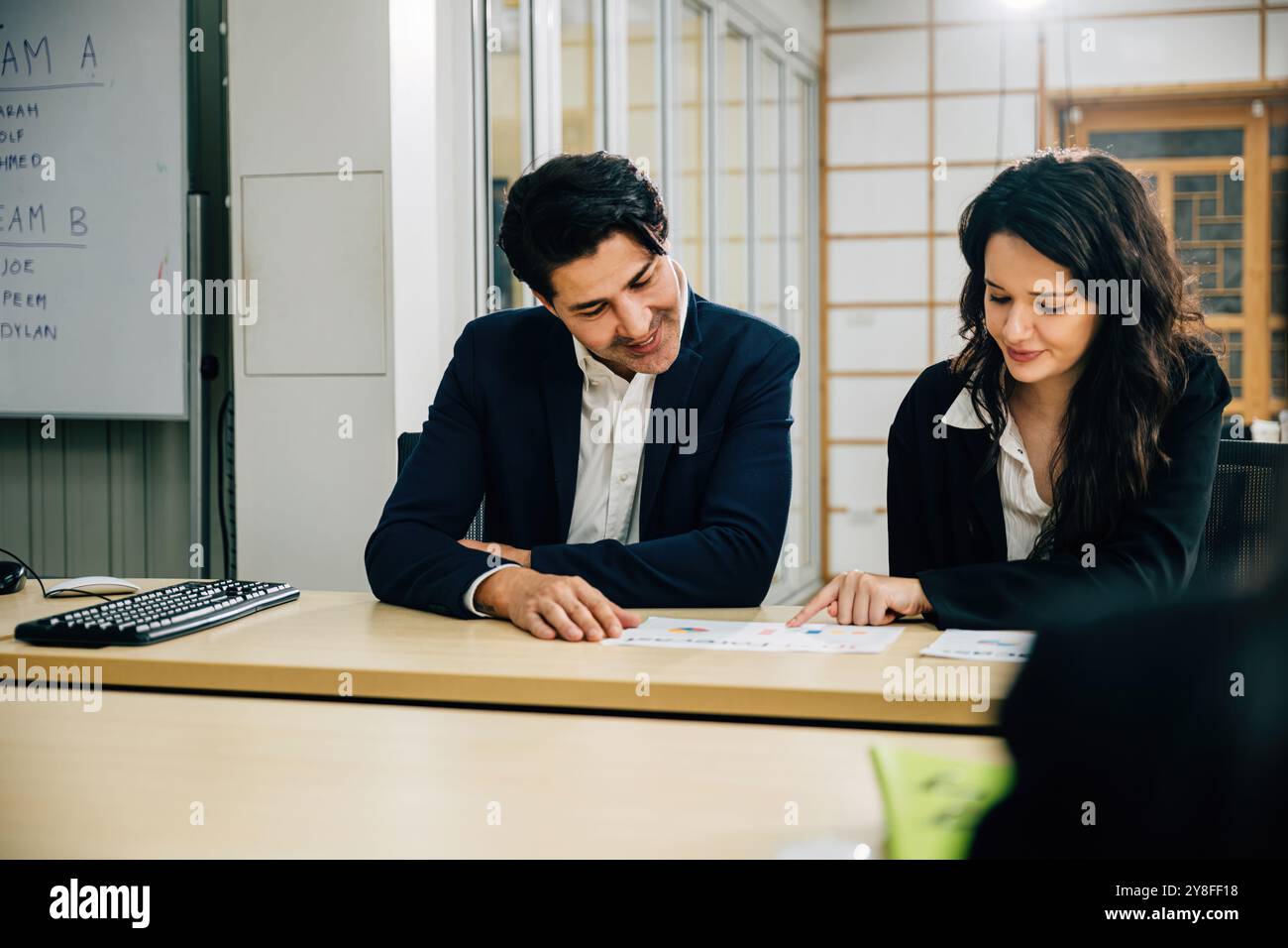 In an office setting, two colleagues engage in a meeting, focusing on ...