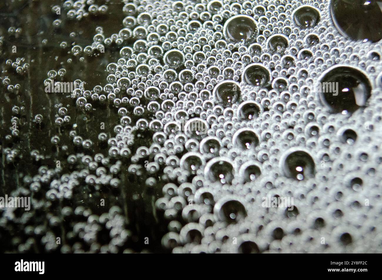 Macro view of bubbles forming on the water surface with dark background ...