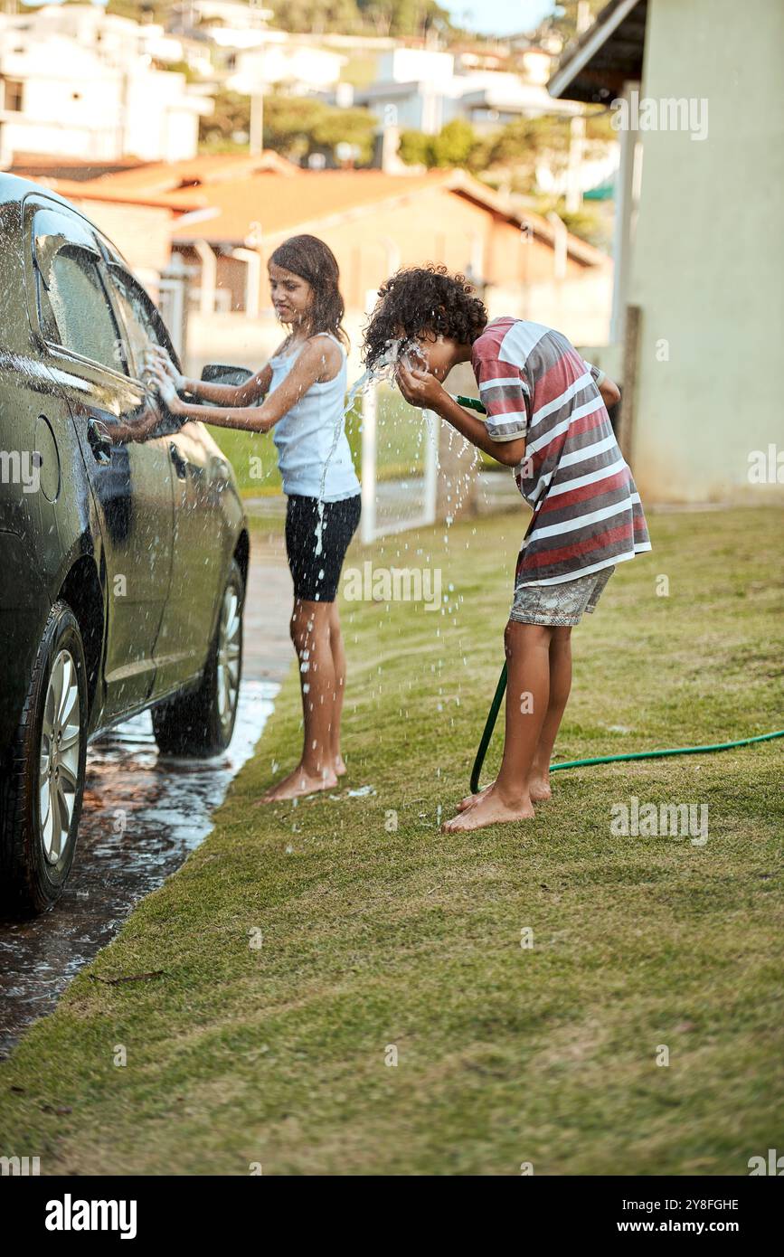 Children, washing car and outdoor with garden hose, foam and drinking ...