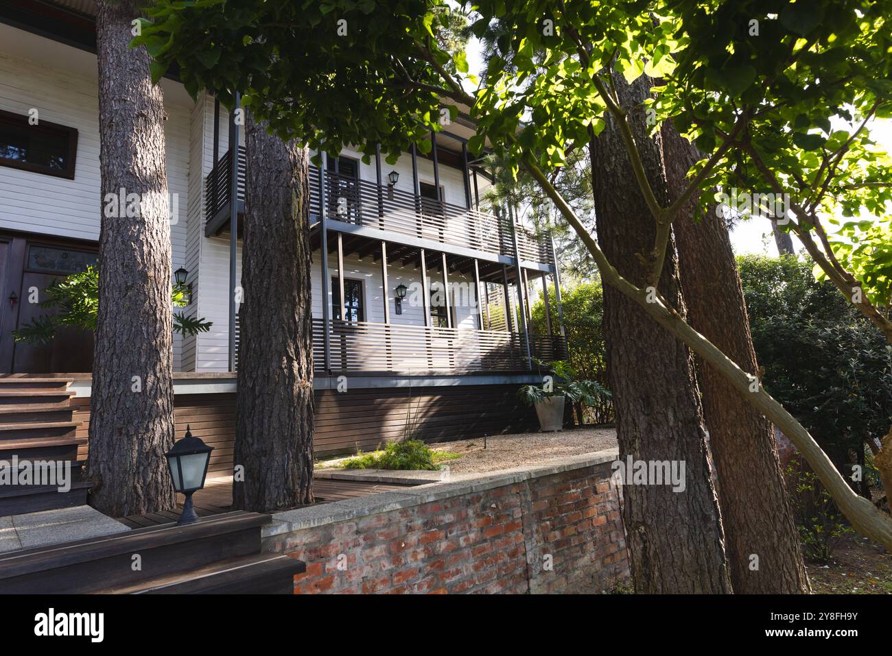 Modern big empty house with two balconys in big green garden with trees ...