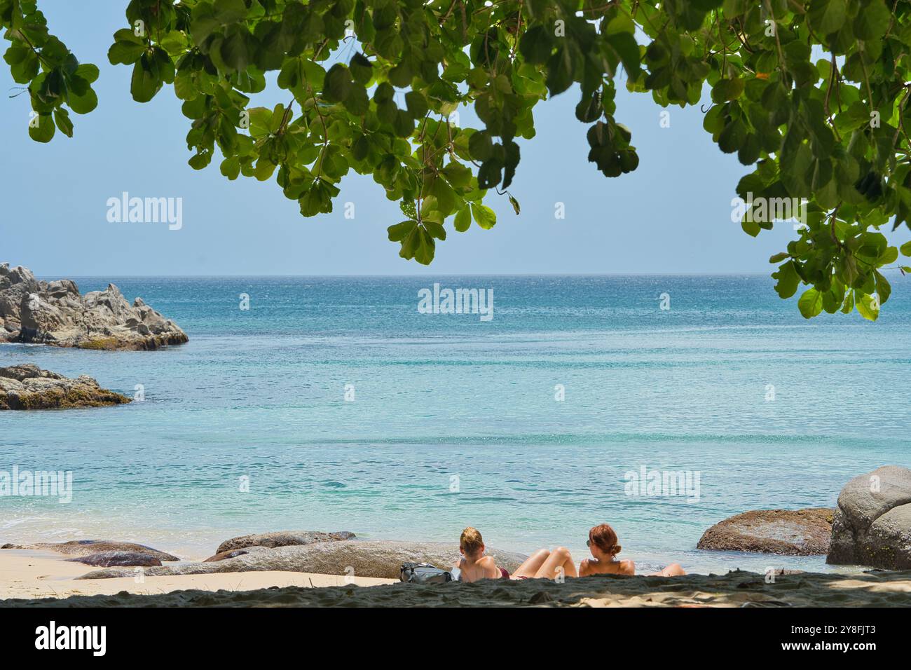 2 female tourist sitting on the white sandy beach, beautiful sunny day ...