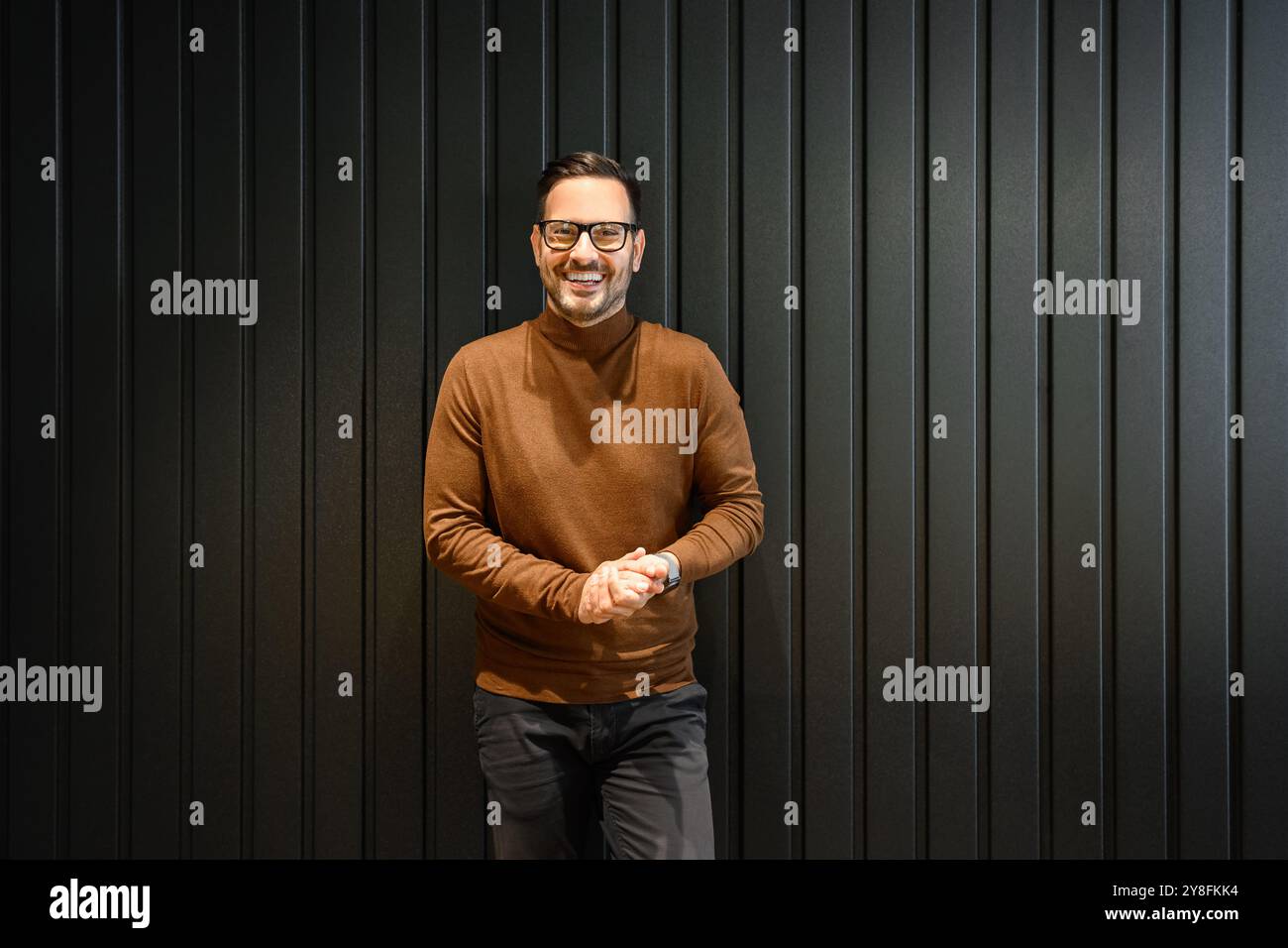 Portrait of handsome CEO with hands clasped smiling at camera and ...