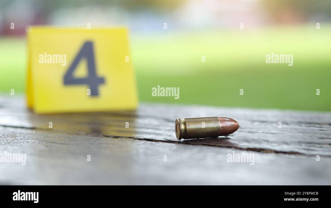 9 mm pistol bullet lying on dark wooden bench with blur number 4 sign ...