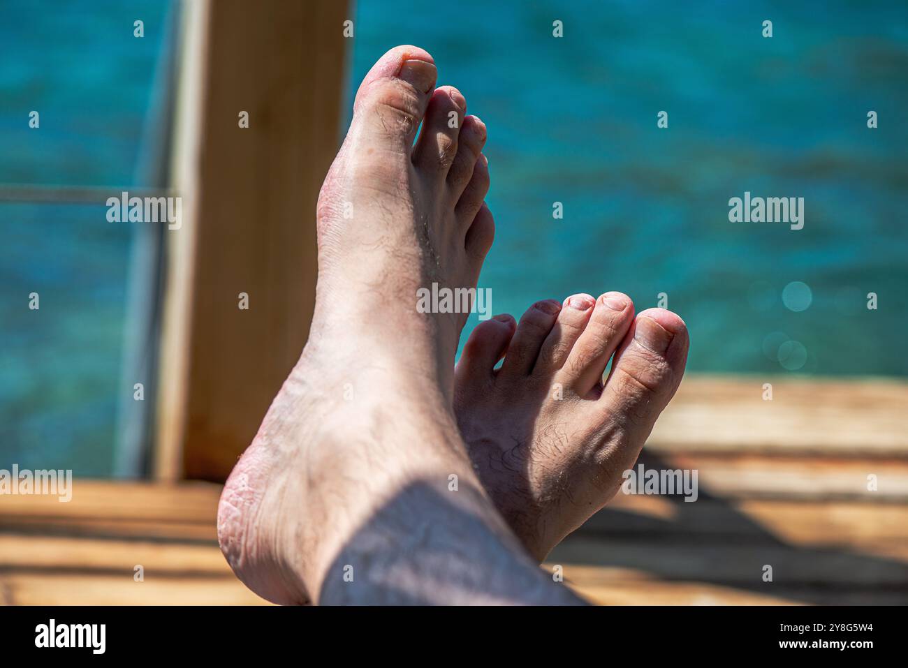 A close-up shot of a man's toes and feet resting in the warm sand by ...
