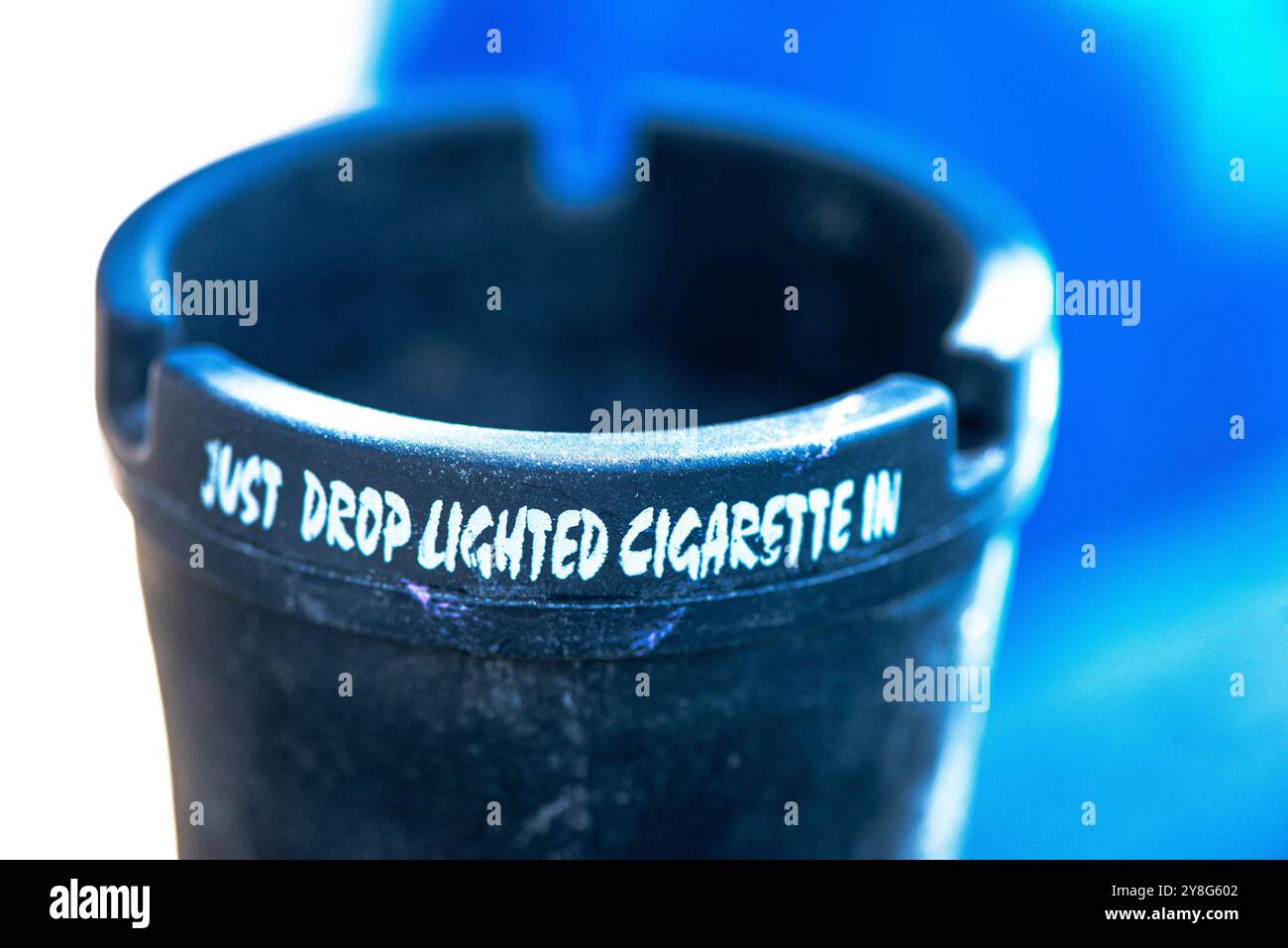 A close-up photo of an ashtray featuring a sign that reads "Just Drop ...