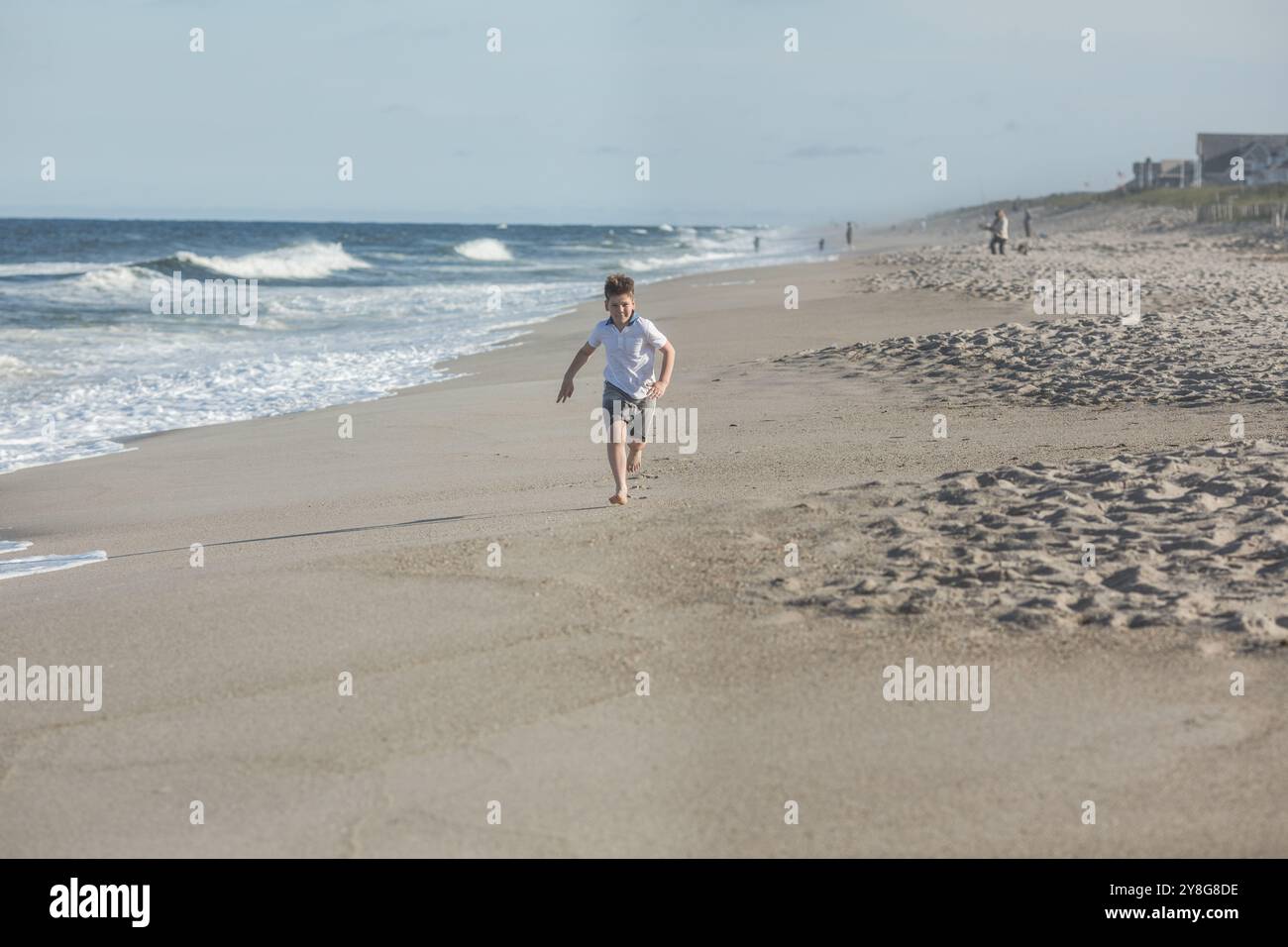 Teenage male walking into the surf on a tropical beach. Sunny day with ...