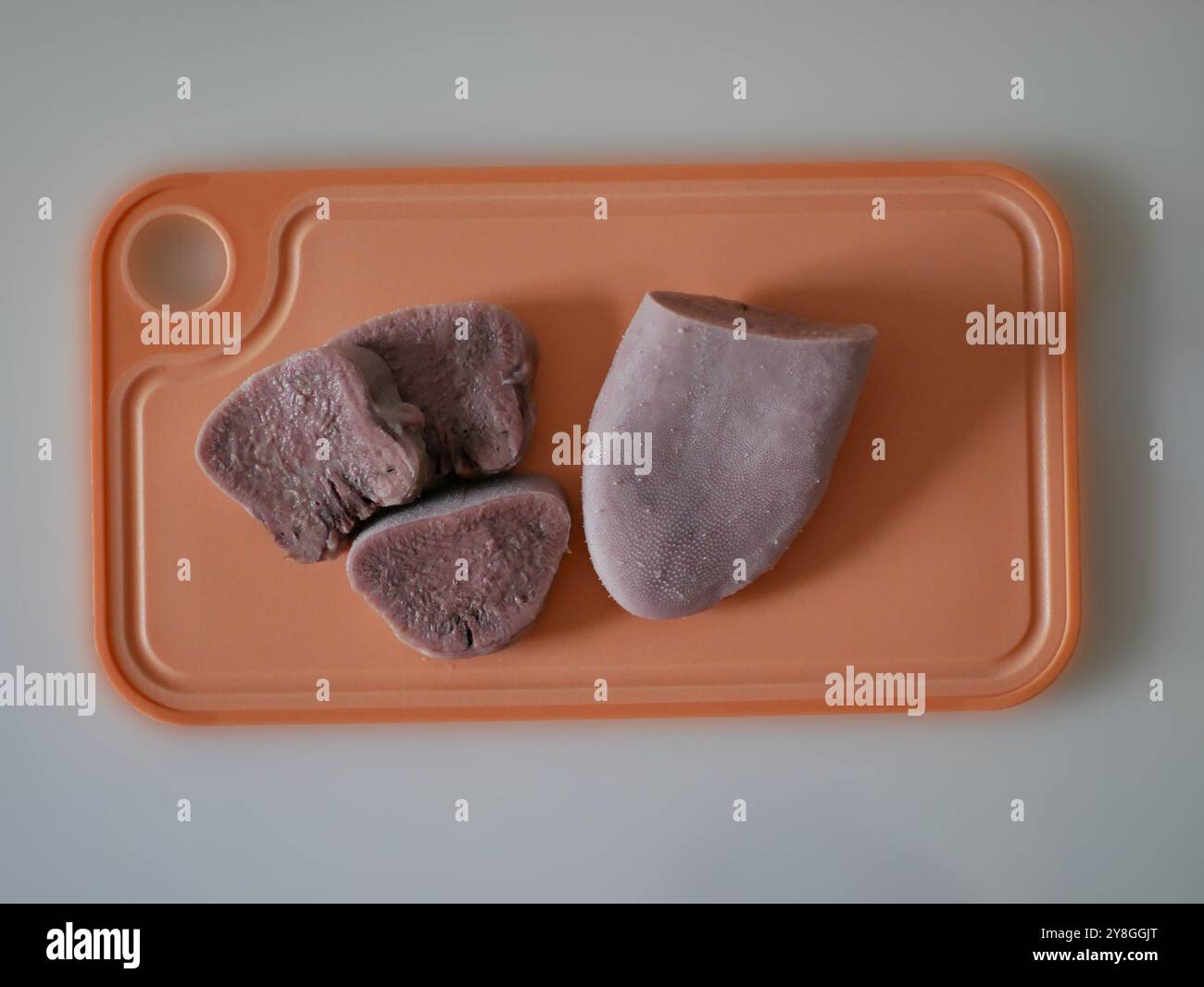 Cut boiled beef tongue on a plastic cutting board Stock Photo - Alamy