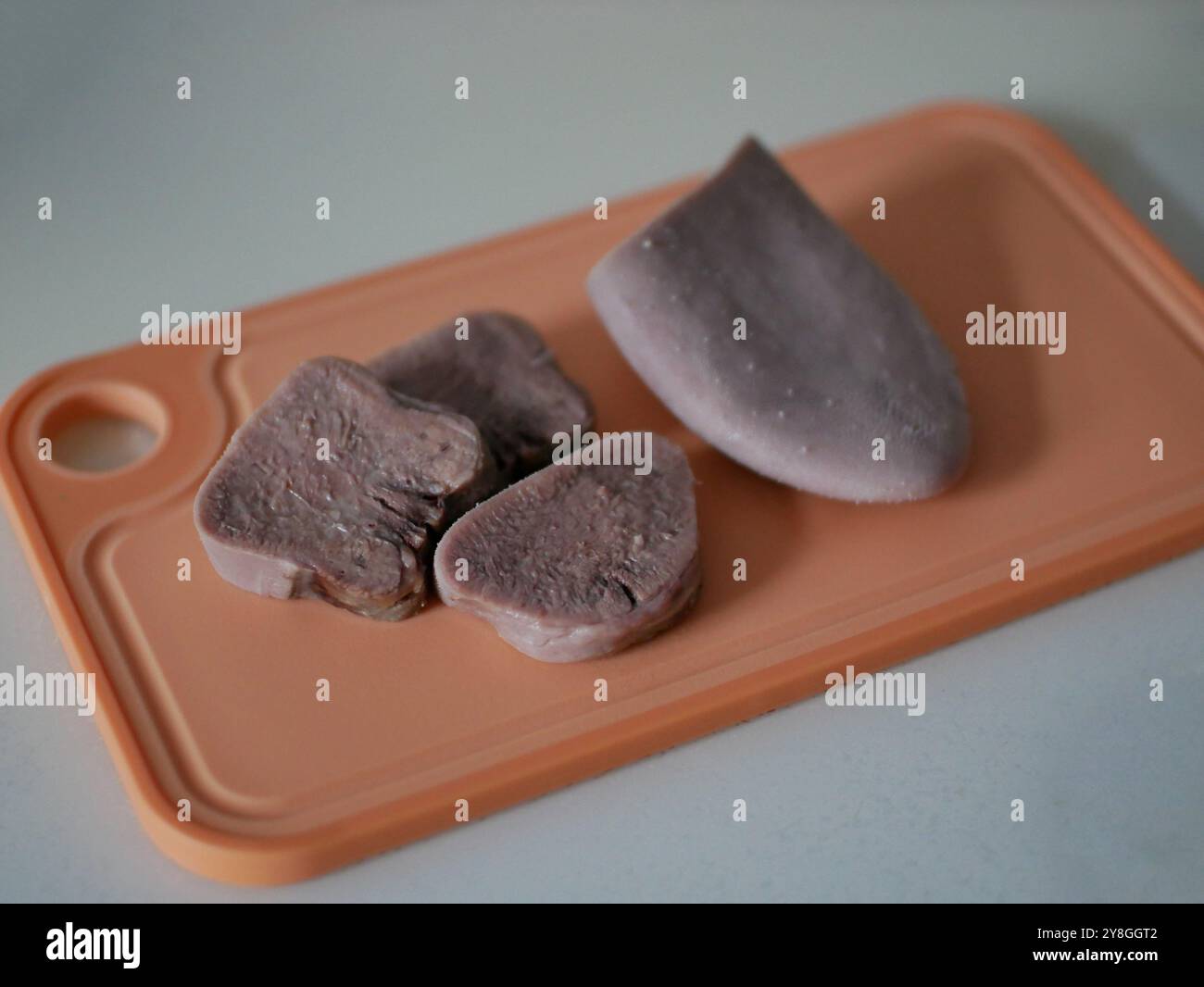 Cut boiled beef tongue on a plastic cutting board Stock Photo - Alamy