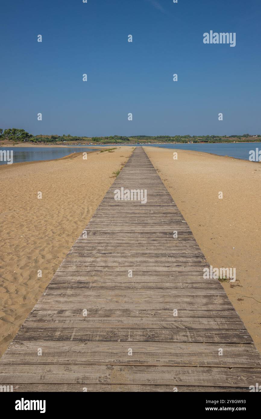 A beach surrounded by the sea on both sides, with a wooden pier at ...