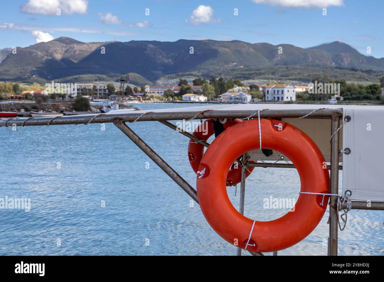 Red lifeline fixed on a boat in a port. City and mountains in the ...