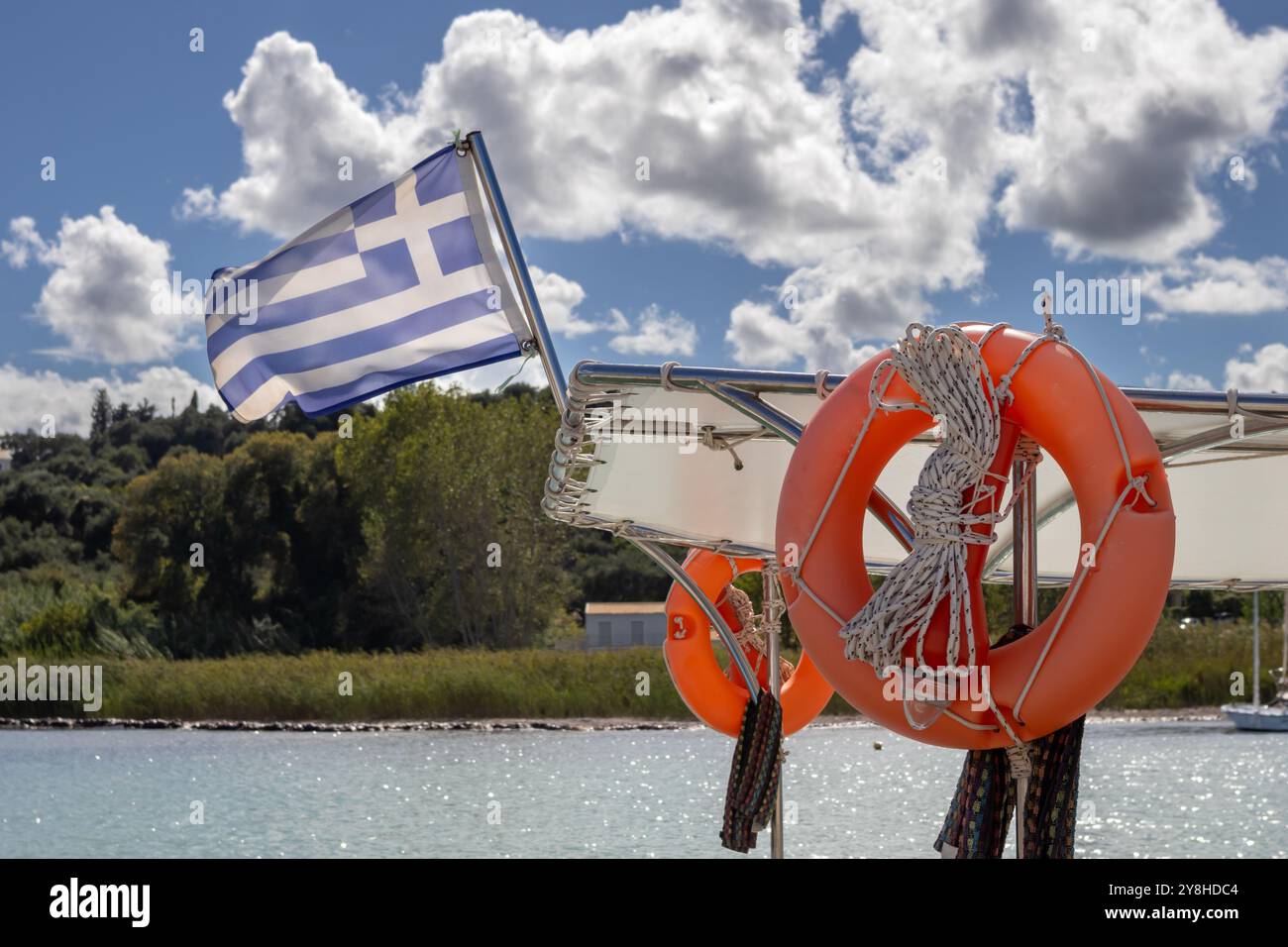 Red lifeline fixed on a boat in a port. Greek flag blowing in the wind ...