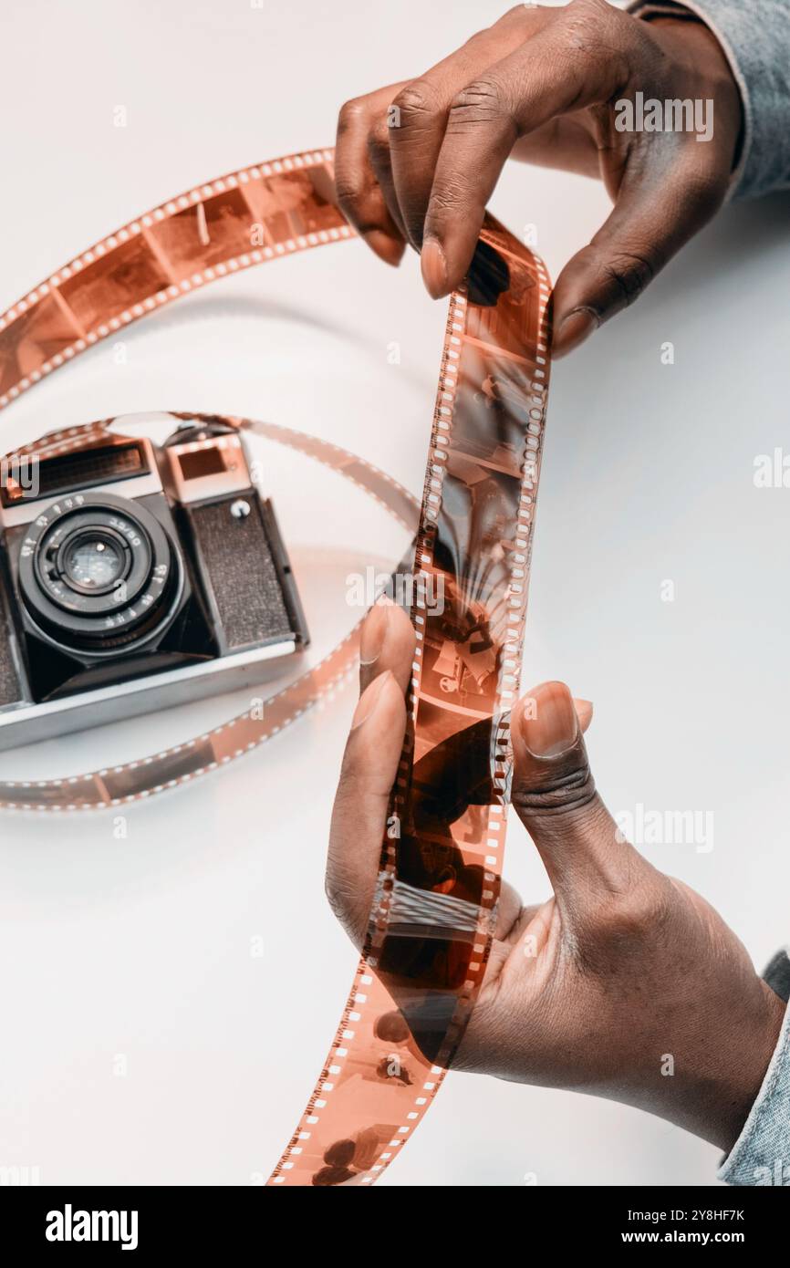 Black man hands holding vintage film strip with retro camera on white ...
