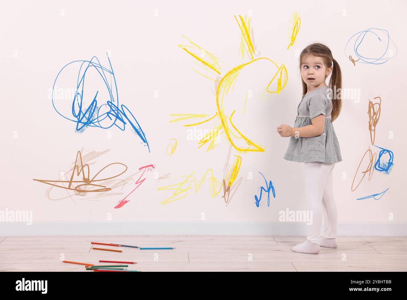 Little child near white wall with drawings Stock Photo - Alamy
