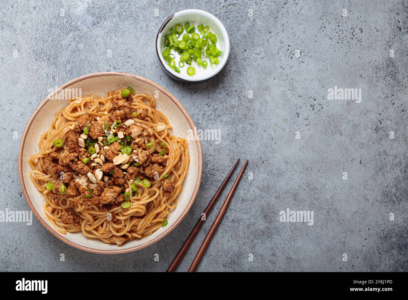 Dan dan noodles served with chopsticks and green onions top view ...