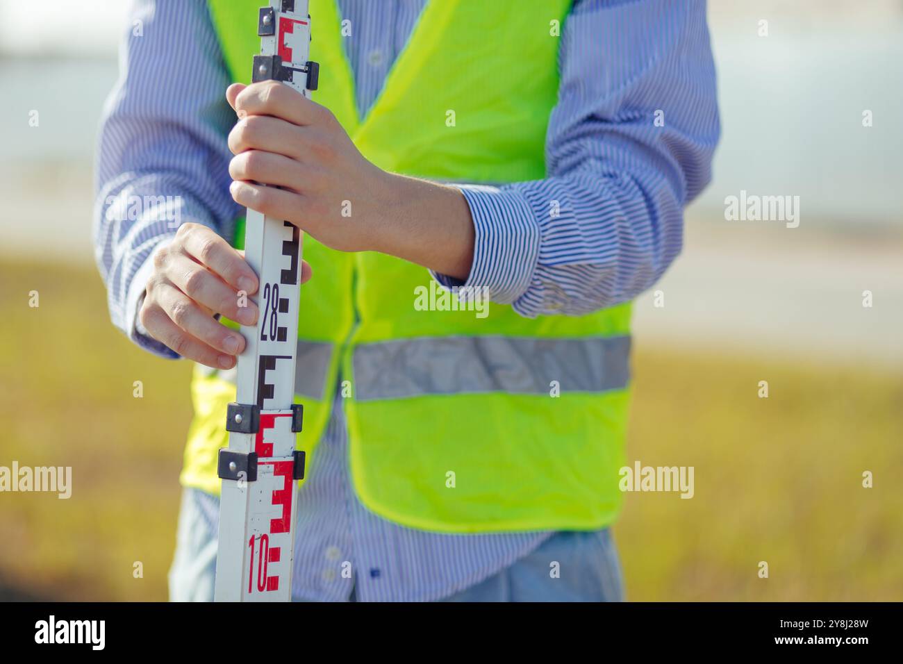 Worker is unfolding leveling rod on construction site Stock Photo - Alamy