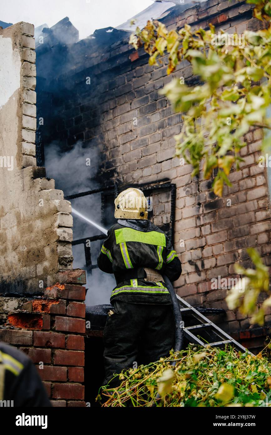 Firefighter extinguish fire in house using spraying hose Stock Photo ...