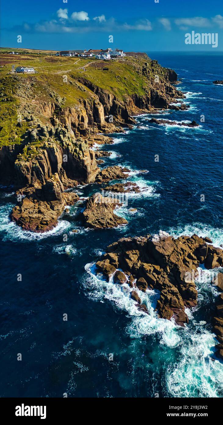 Aerial view of rugged coastal cliffs meeting the ocean, with waves ...