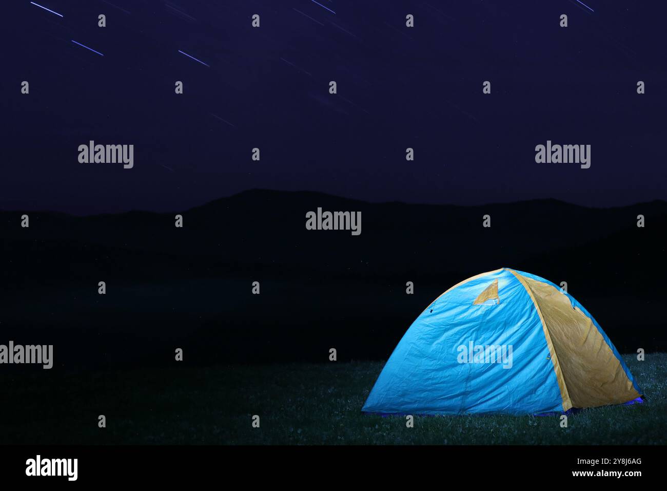 Modern camping tent in wilderness at night, slow shutter speed effect ...