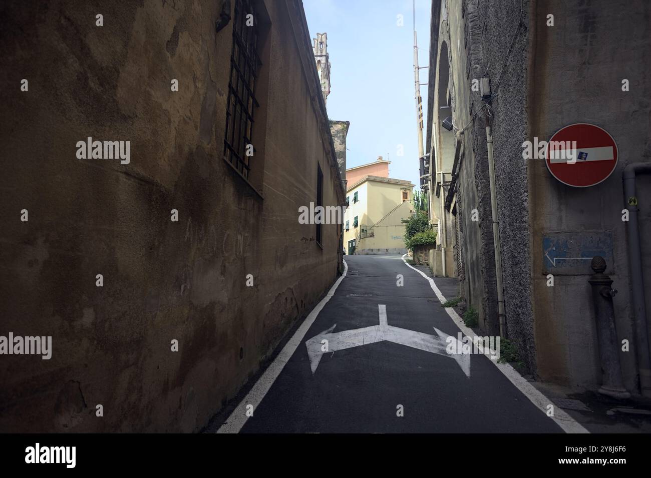 Narrow alley on a slope next to a bridge with a stop sign on the ground ...