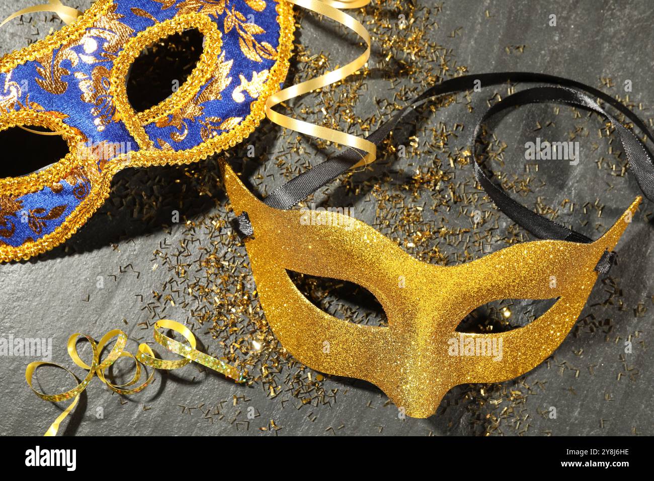 Beautiful carnival masks and confetti on gray textured table, flat lay ...