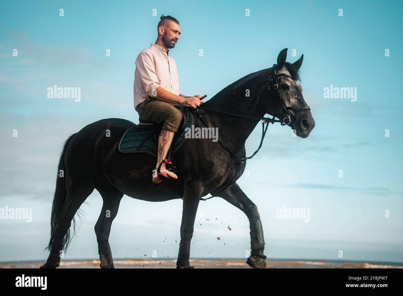 Man with tattoos riding a horse Stock Photo - Alamy