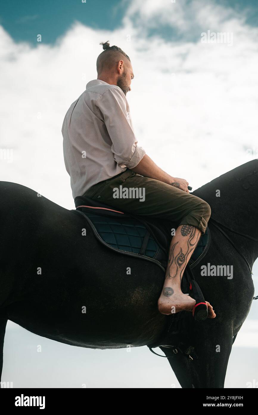 Man with tattoos riding a horse Stock Photo - Alamy