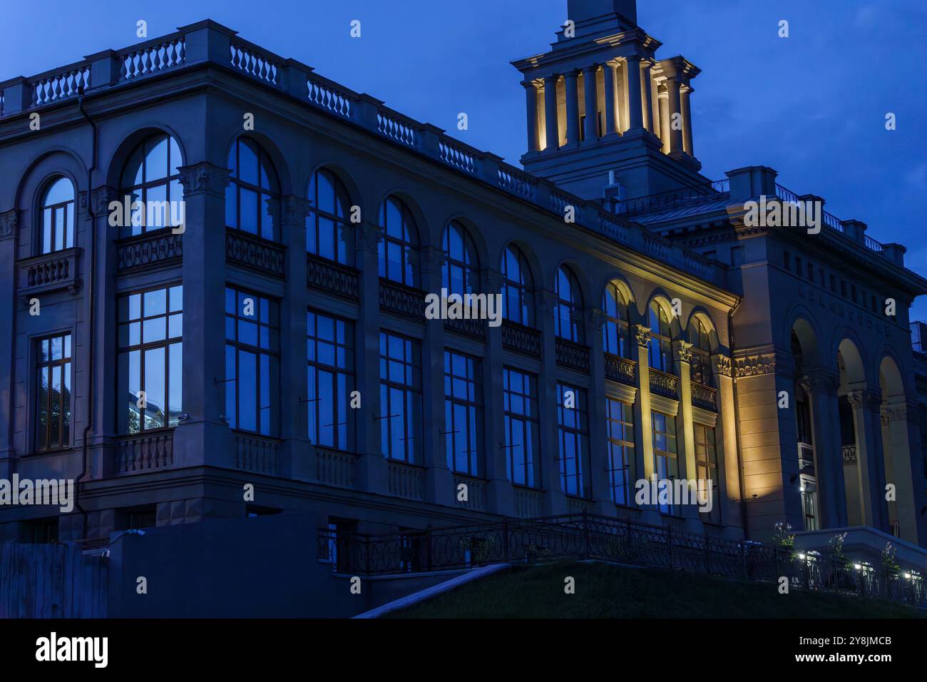A historic building with large windows is illuminated at dusk ...