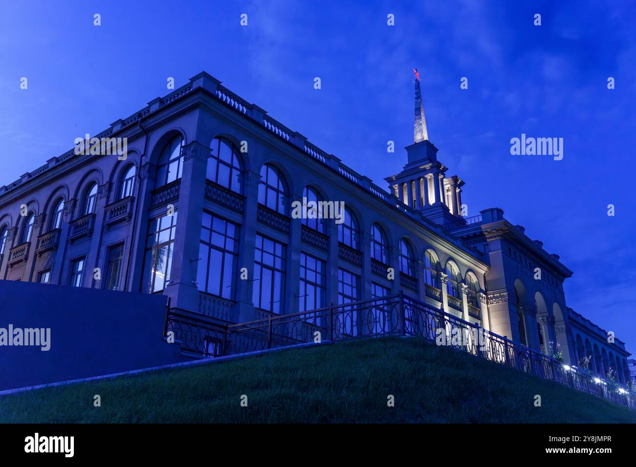 A historic building with large windows is illuminated at dusk ...