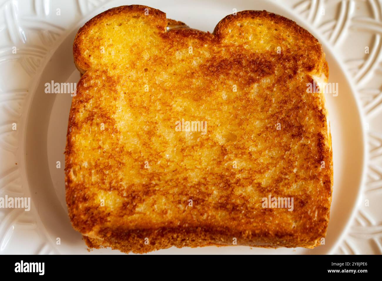A hot grilled cheese on a white plate made at home with basic loaf ...