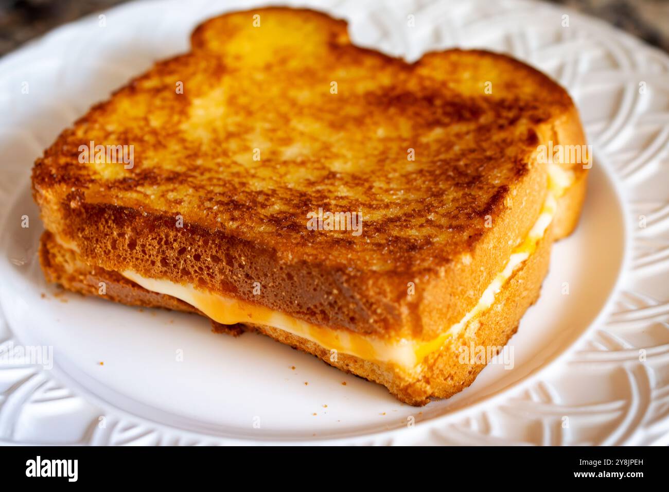 A hot grilled cheese on a white plate made at home with basic loaf ...