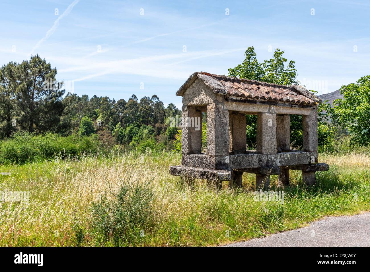 Historic stone granary stands amid lush greenery under a clear blue sky ...