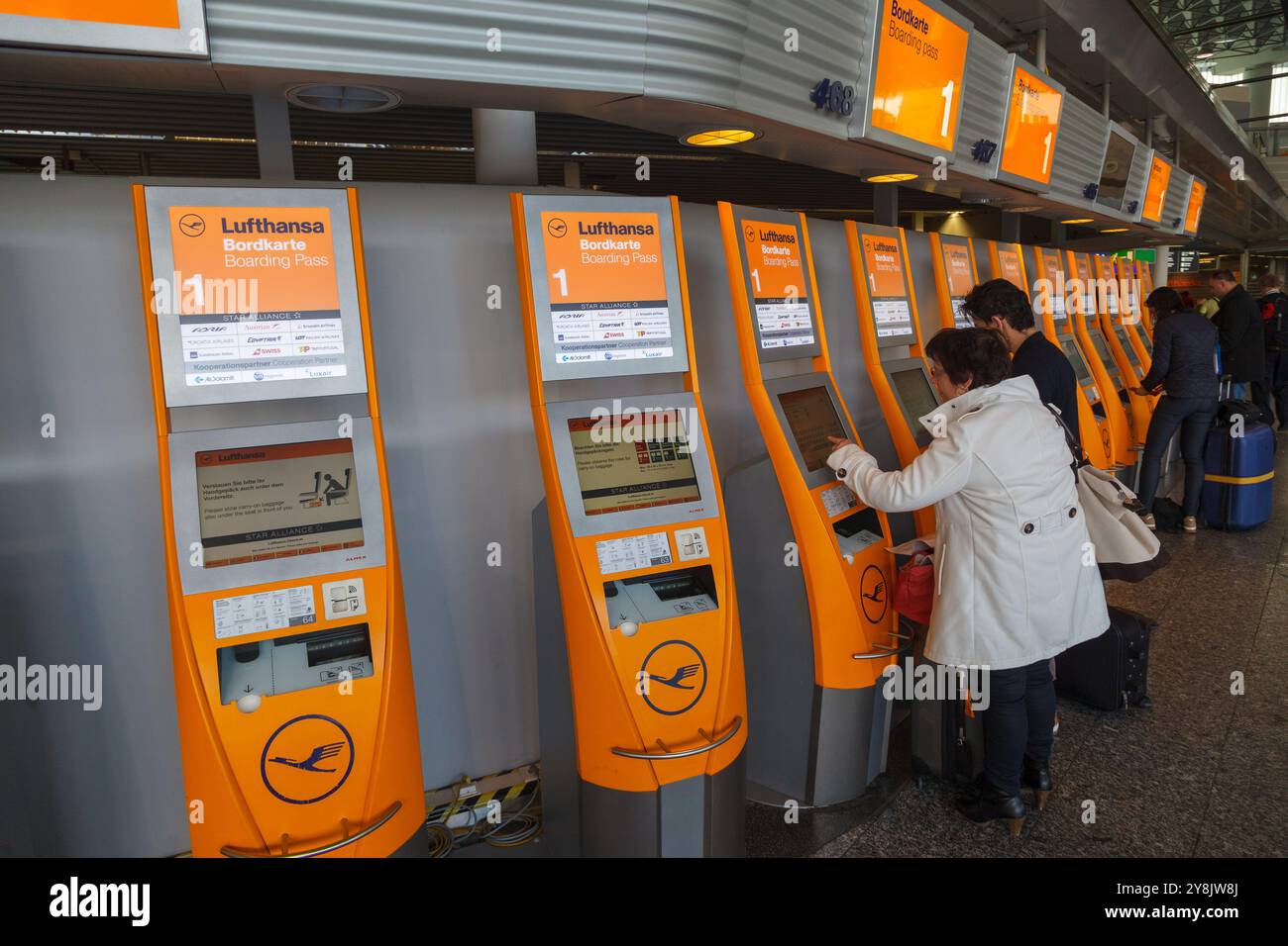 Passengers using a set of auto check-in machines of Lufthansa inside ...