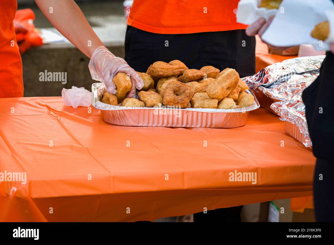 A gloved hand reaches for traditional bannock bread in a foil container ...