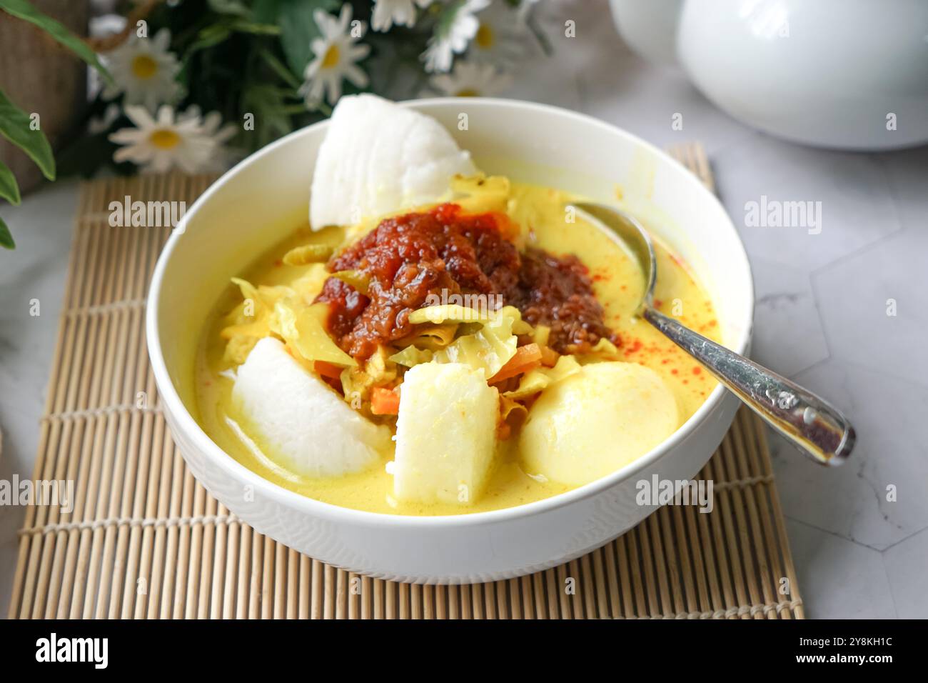 A bowl of “Lontong” or rice cake and coconut gravy with tumeric, chilli ...