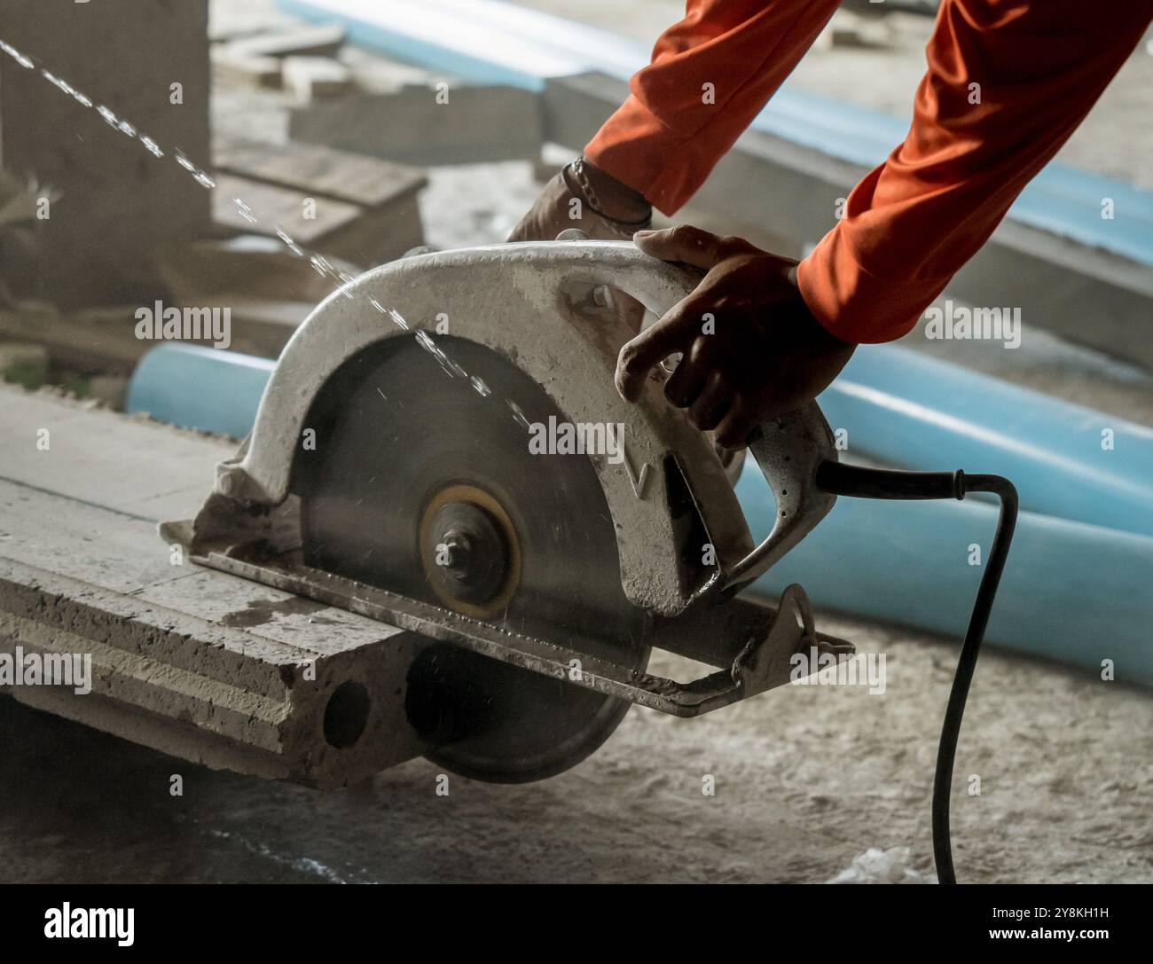 A builder using a circular saw to cut a large concrete piece Stock ...