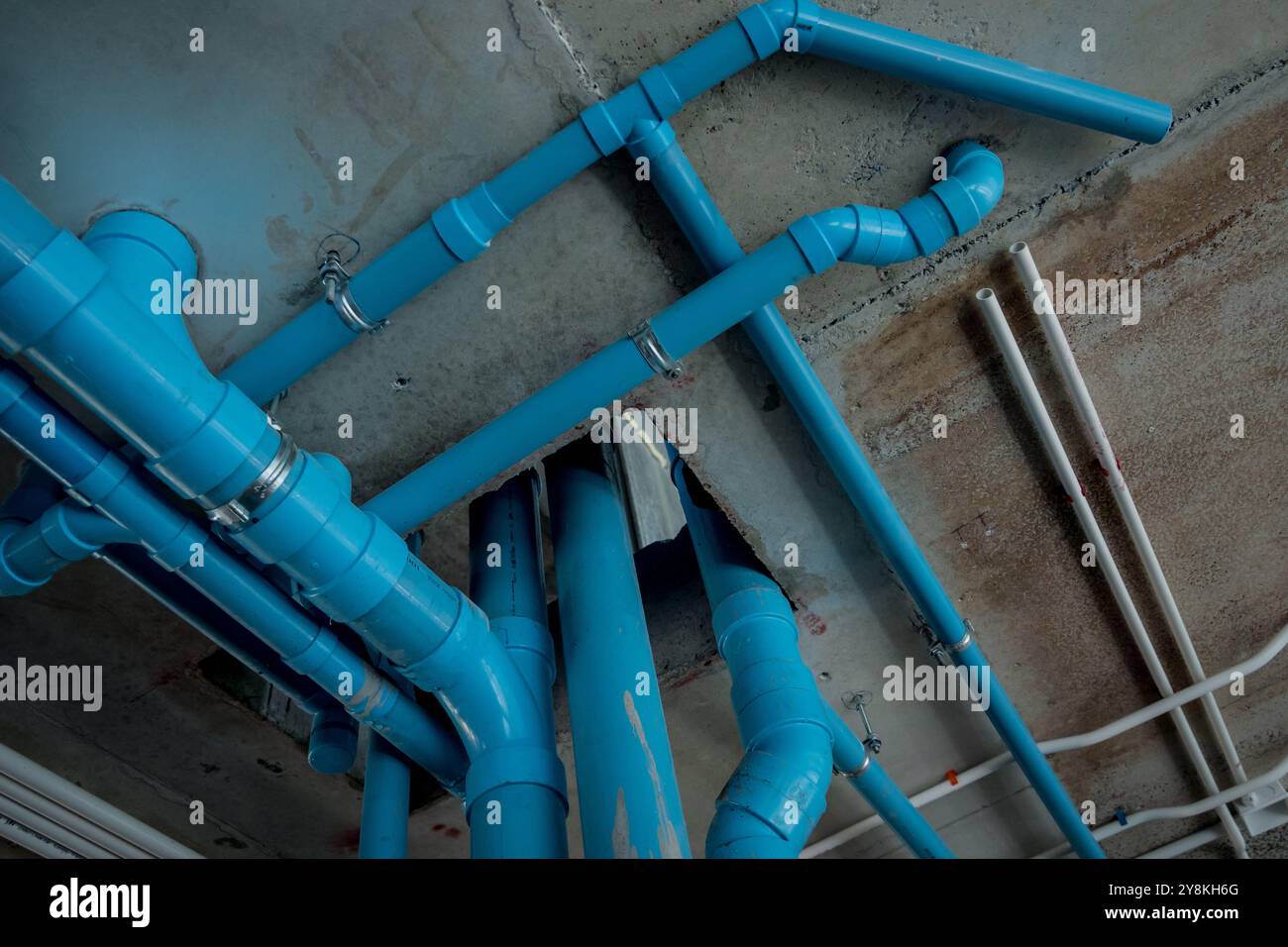A bright blue pipes attached to a solid concrete wall Stock Photo - Alamy
