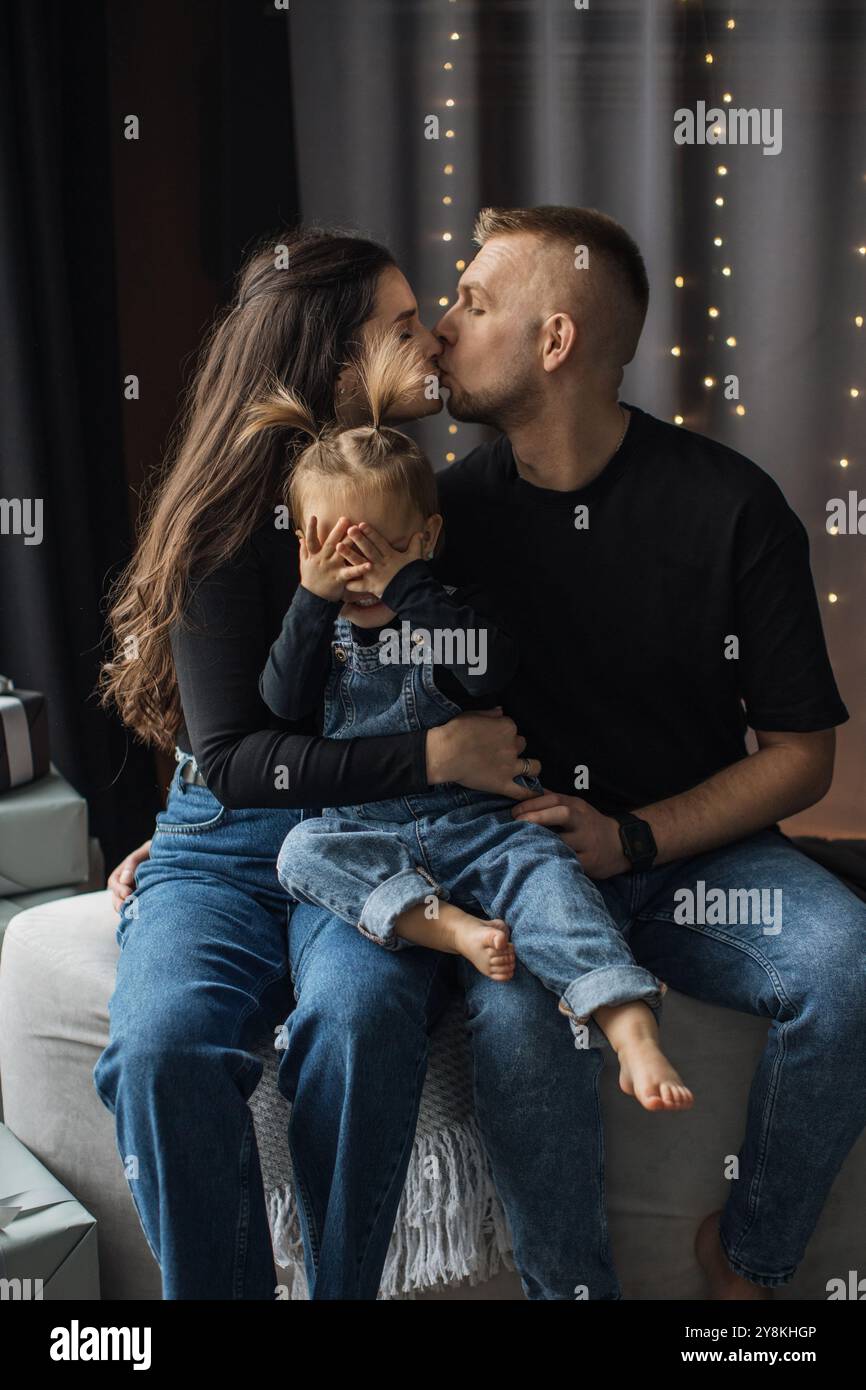 Loving family moment with parents kissing child Stock Photo - Alamy