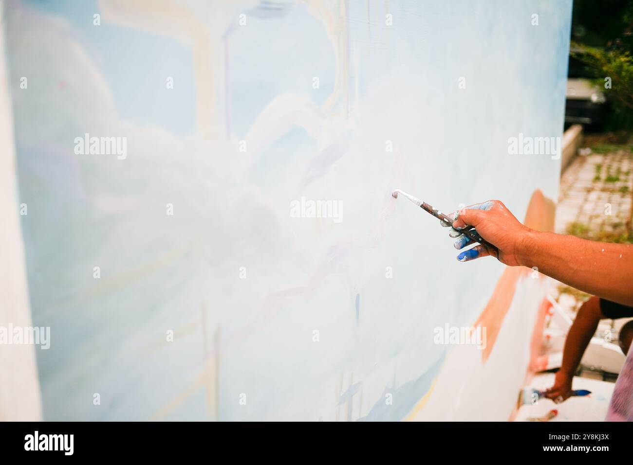 close up of mural artist hand holding paintbrush drawing on the wall ...