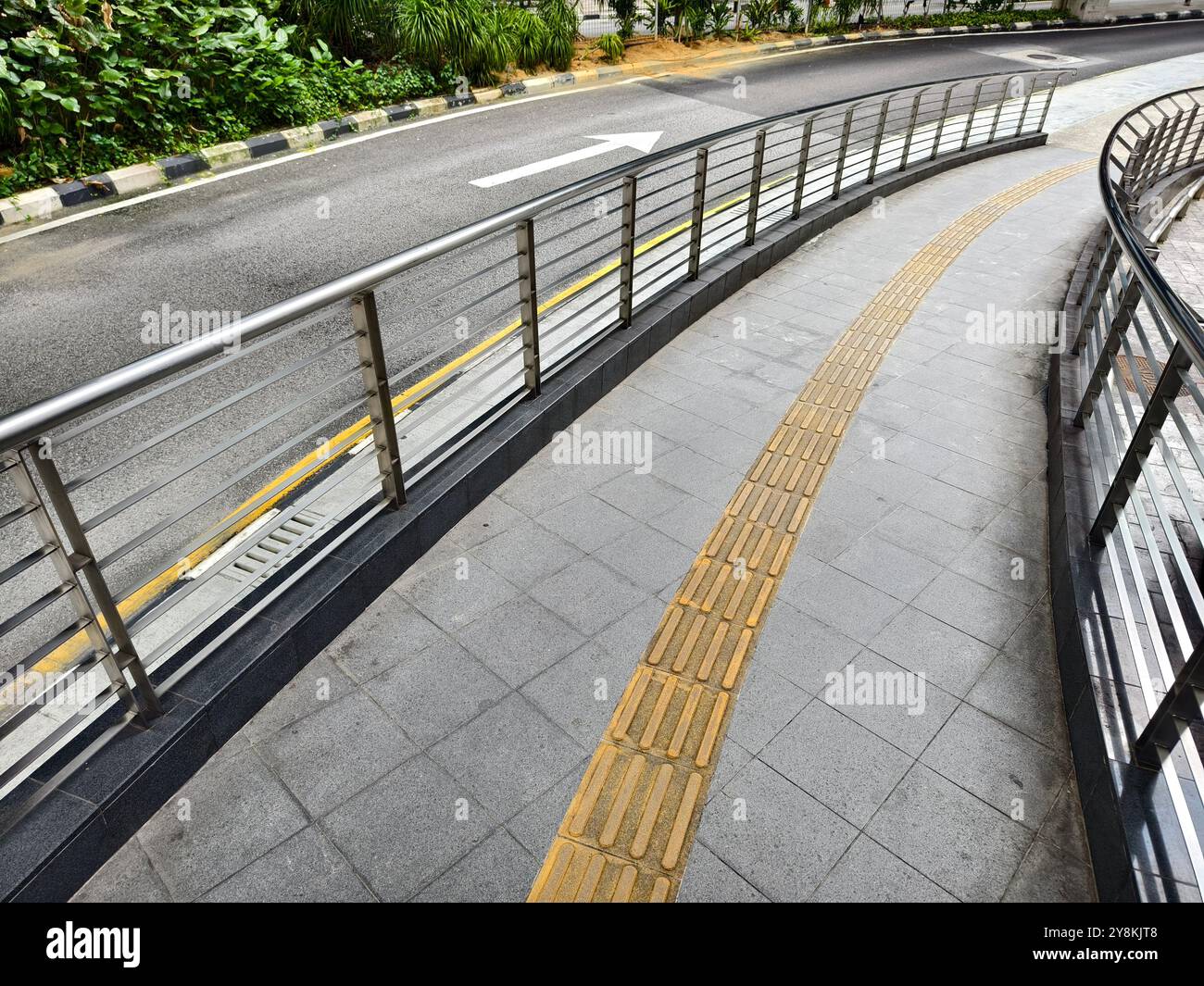 Curved path with guardrail and yellow line for blind people along the ...