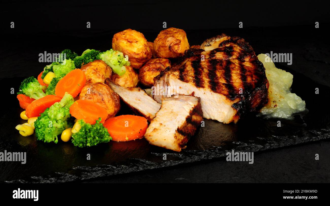 Grilled pork chop meal with roast potatoes and mixed vegetables Stock ...