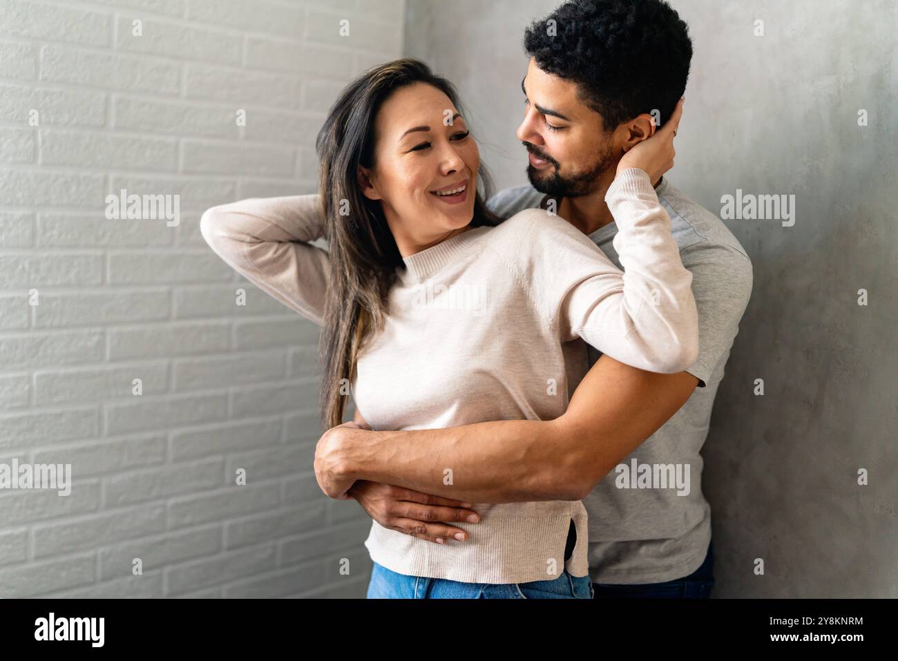The lovely multiethnic couple spends time together, hugging and smiling ...