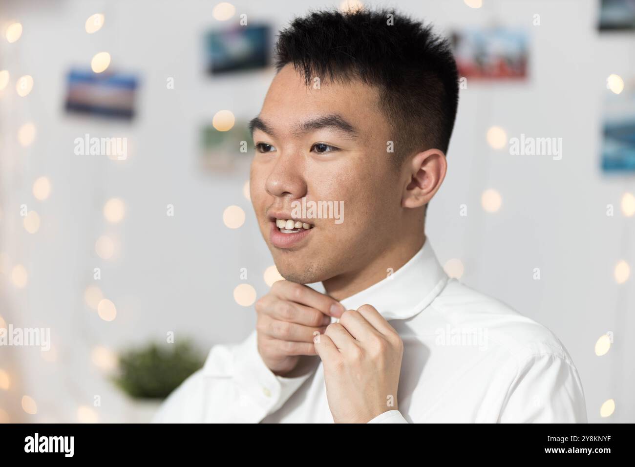 A young business man is buttoning up his shirt in his bedroom, getting ...