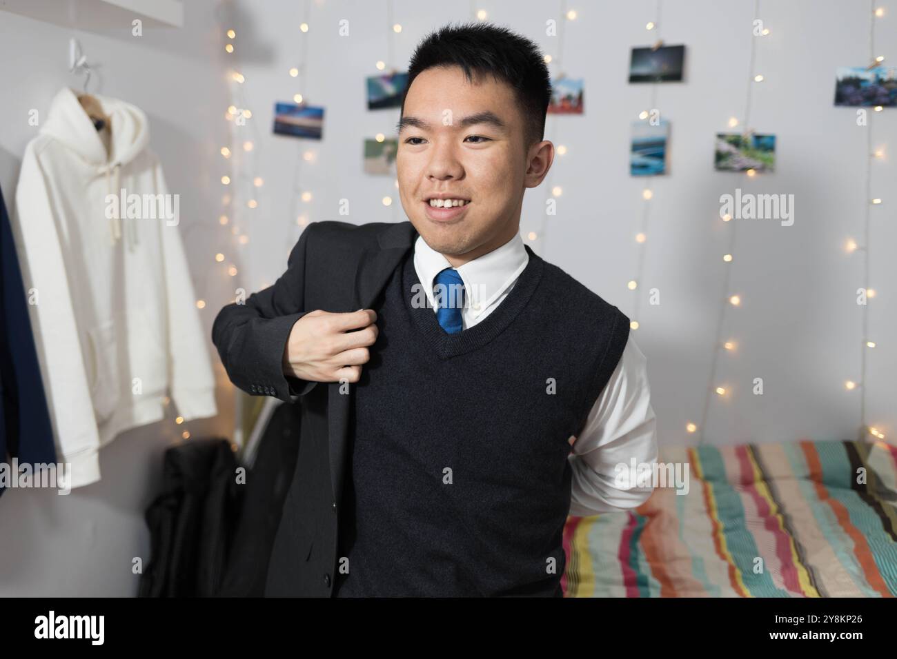 A young man is dressing up and putting on a blazer suit in his bedroom ...