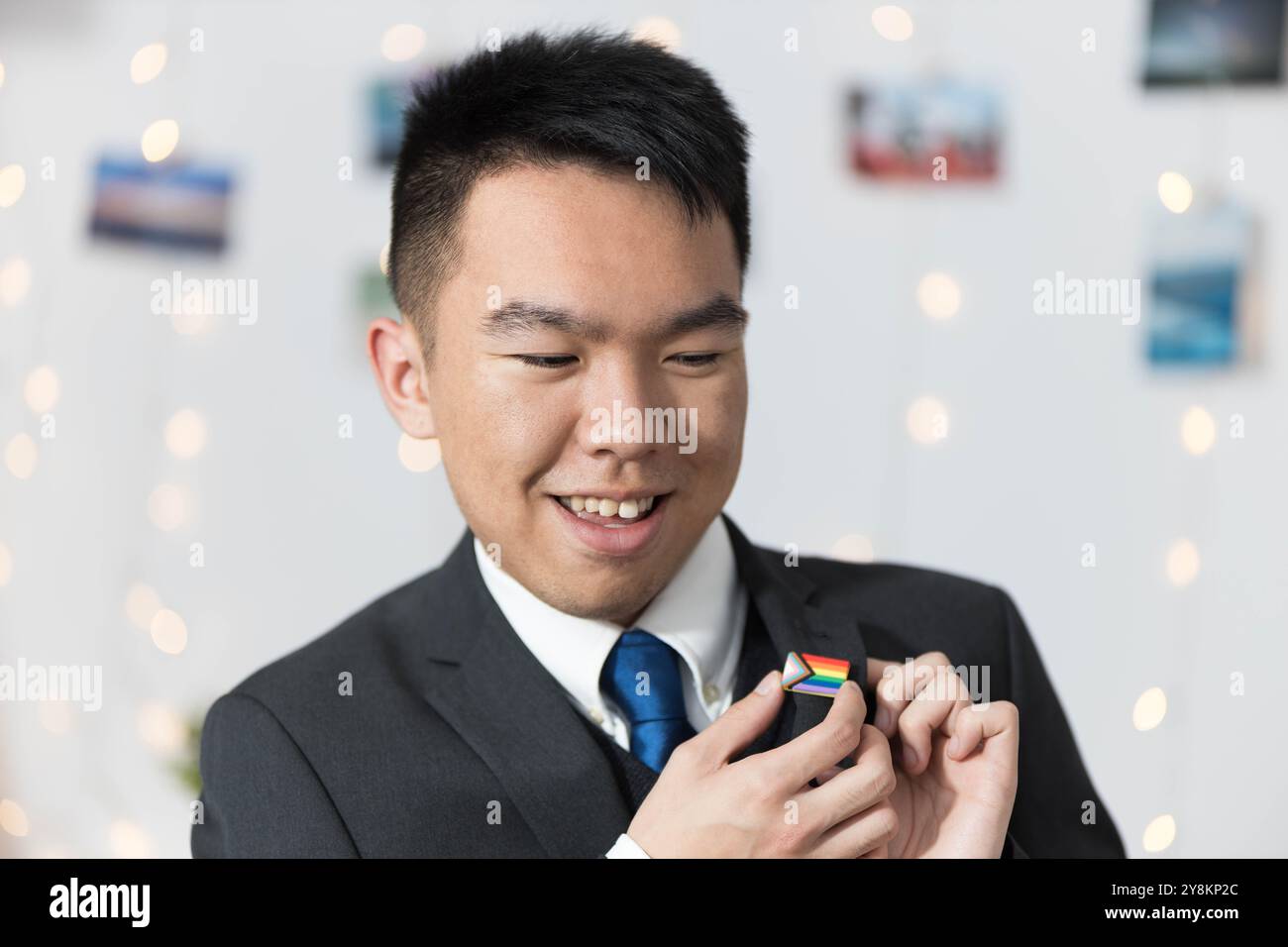 A young business man wearing a suit and tie is adjusting a rainbow ...