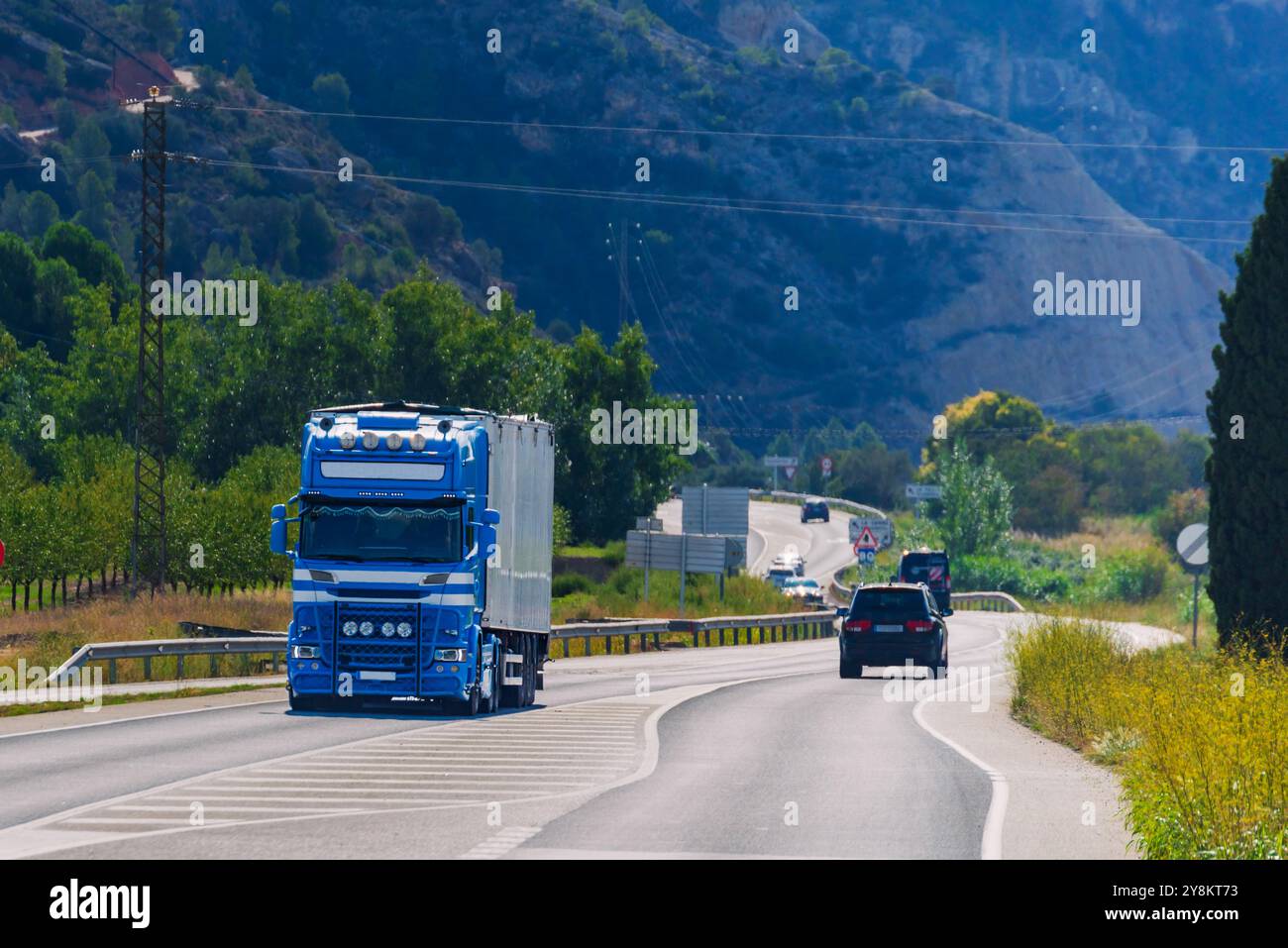 Truck driving on a conventional road with curves and heavy traffic ...