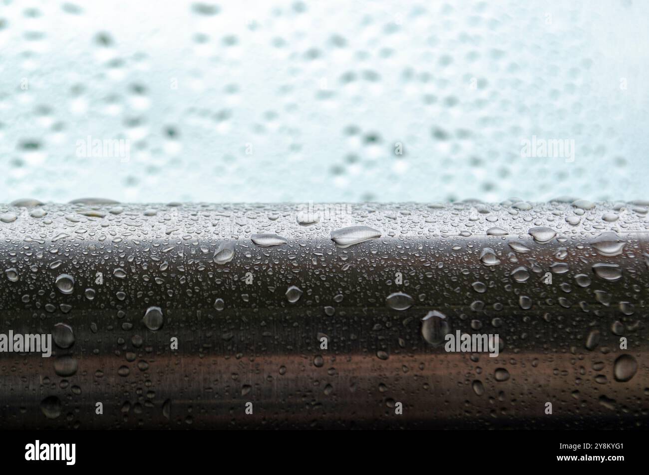Side view of raindrops forming patterns on a smooth surface of metal ...