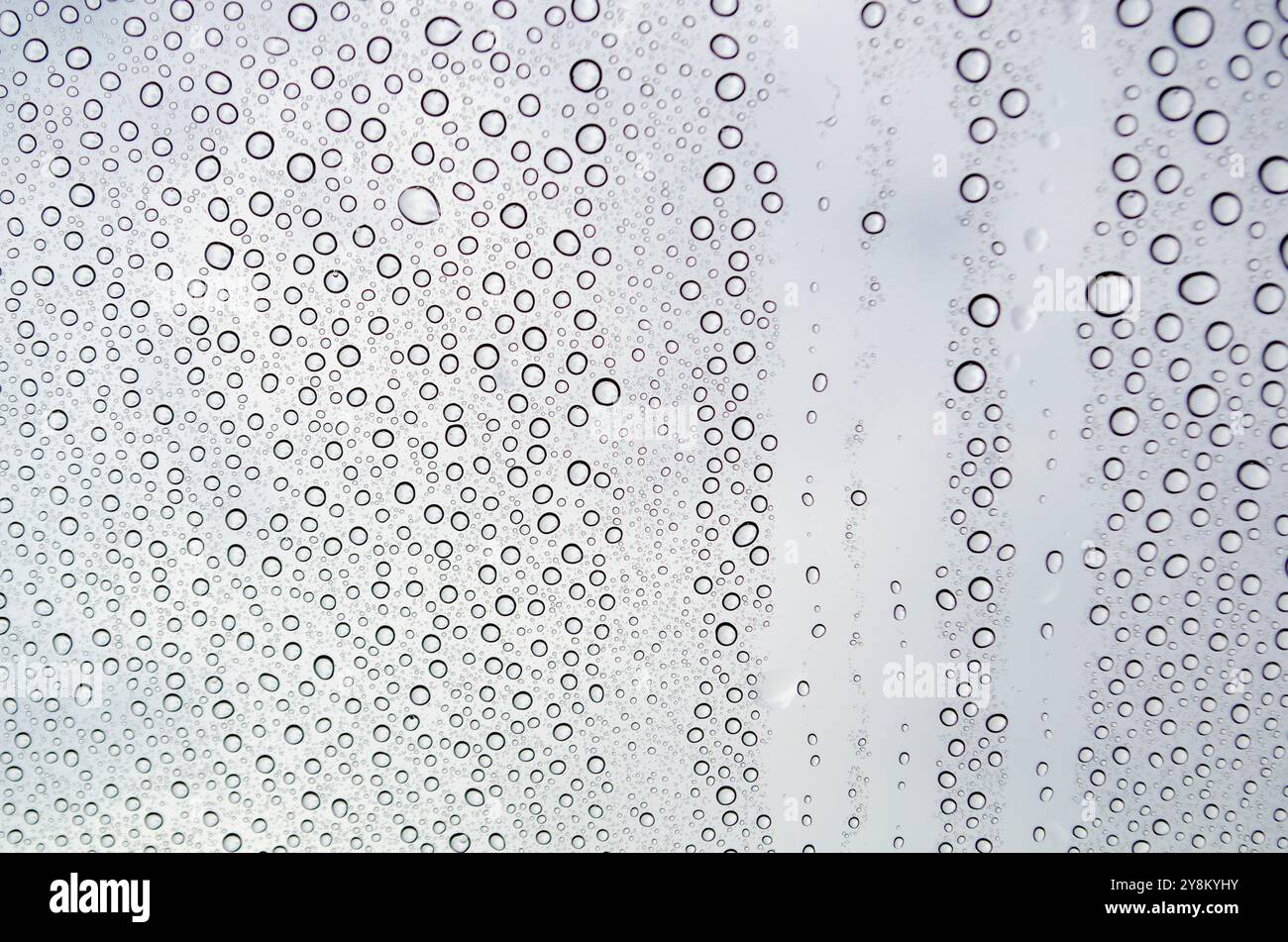 Close-up of droplets clustering on a glass surface after rain. Water ...
